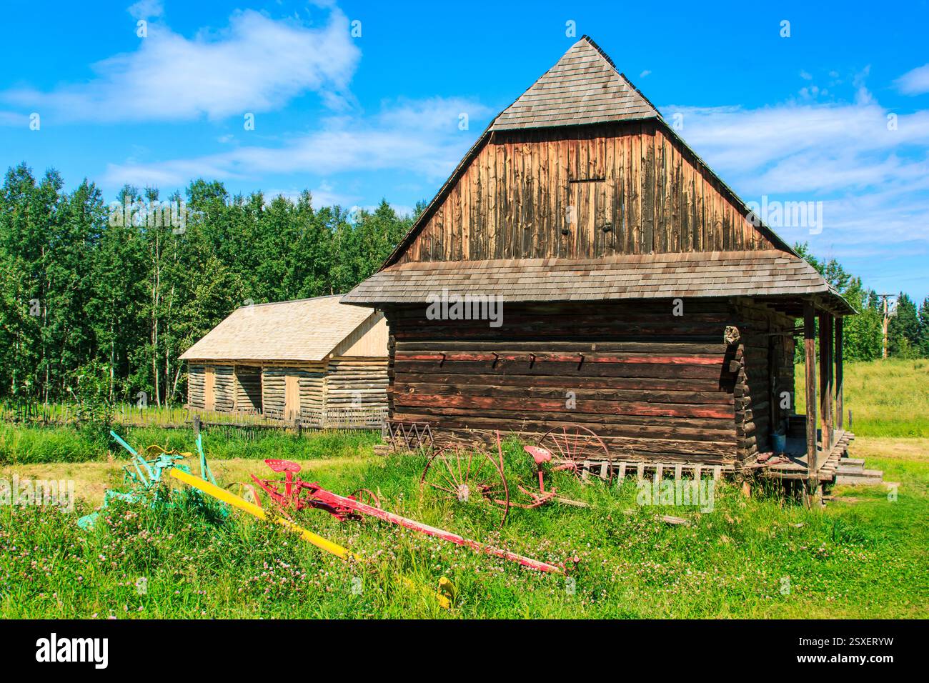 Small house with a green and yellow barn in the background. The barn is ...