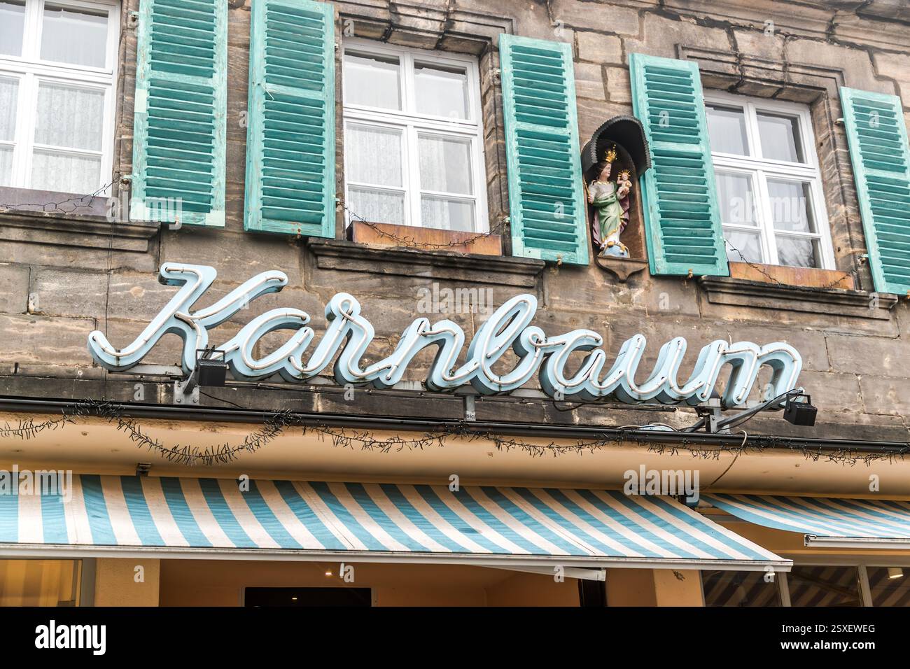 A fish shop in Germany displays a neon sign for "Karbaum" and a statue ...