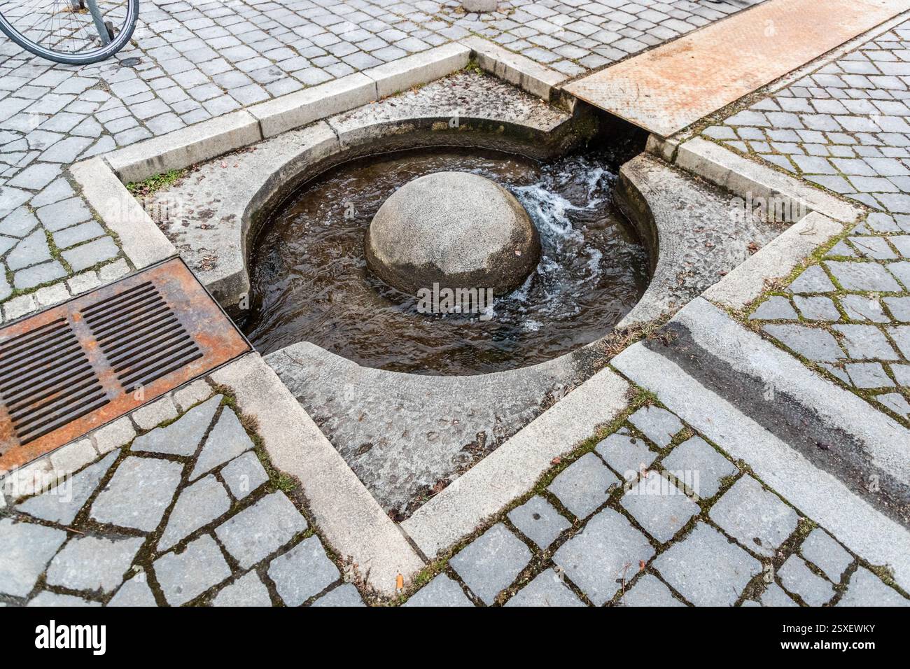 A small water feature in Forchheim's paved streets directs water into a ...