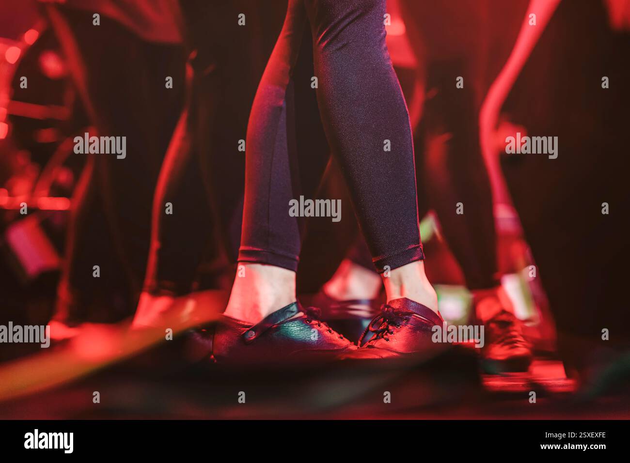 Feet of dancers in black shoes, energetic dance steps on stage, red ...
