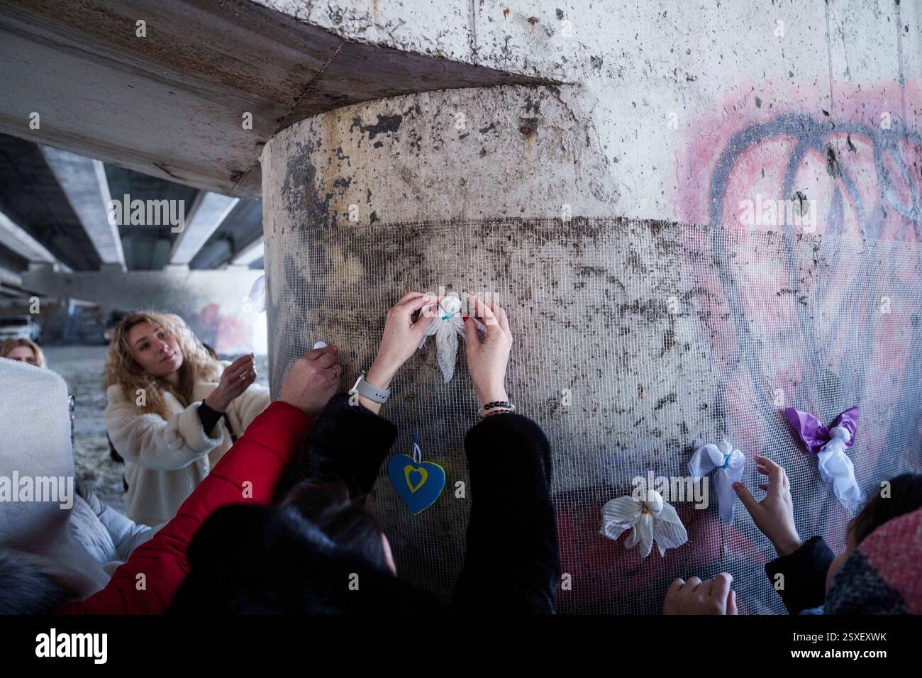 People hang little angels under a destroyed bridge during a memorial ...