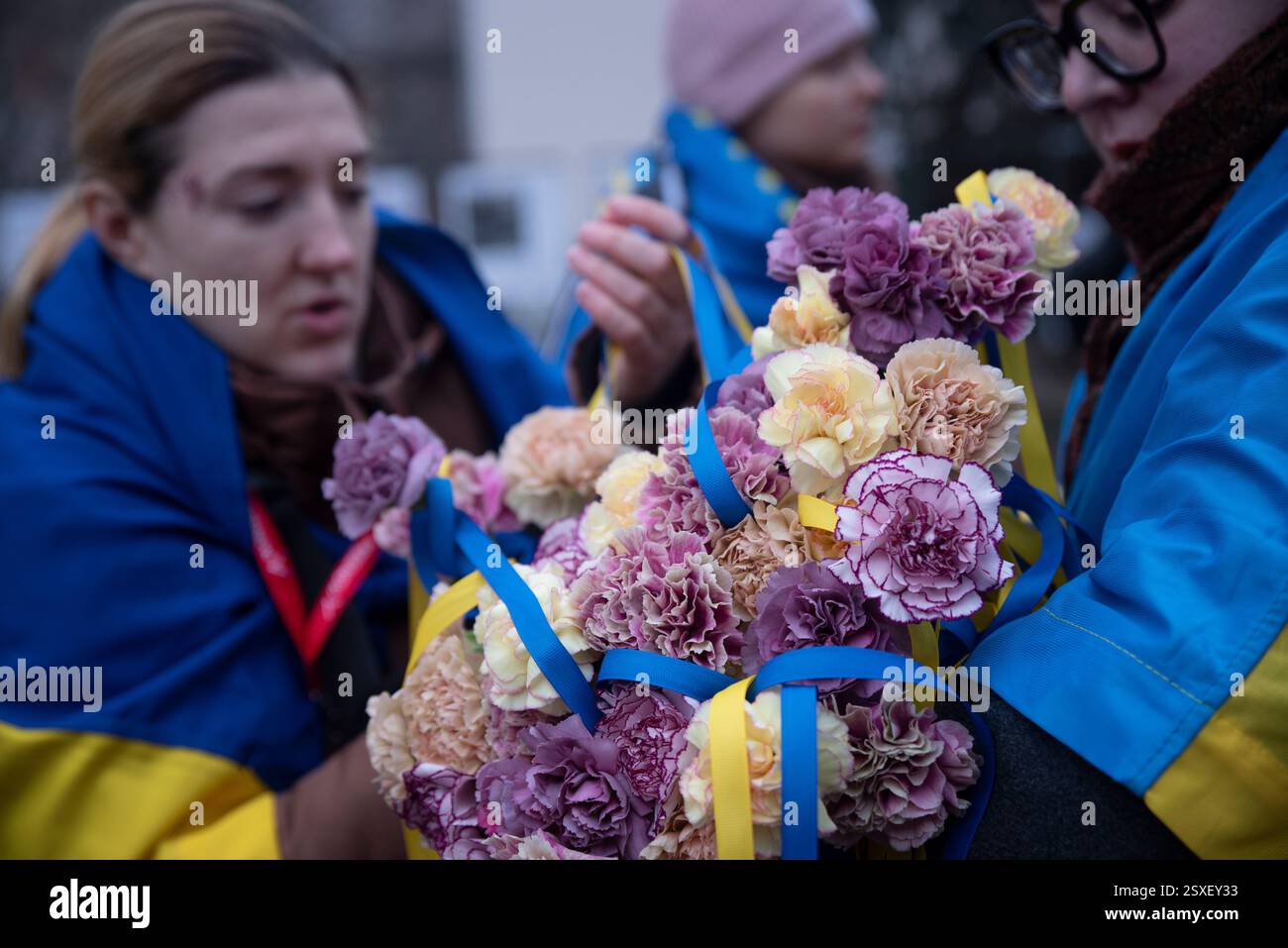A girl holds a bouquet of flowers with ribbons in the colours of the ...
