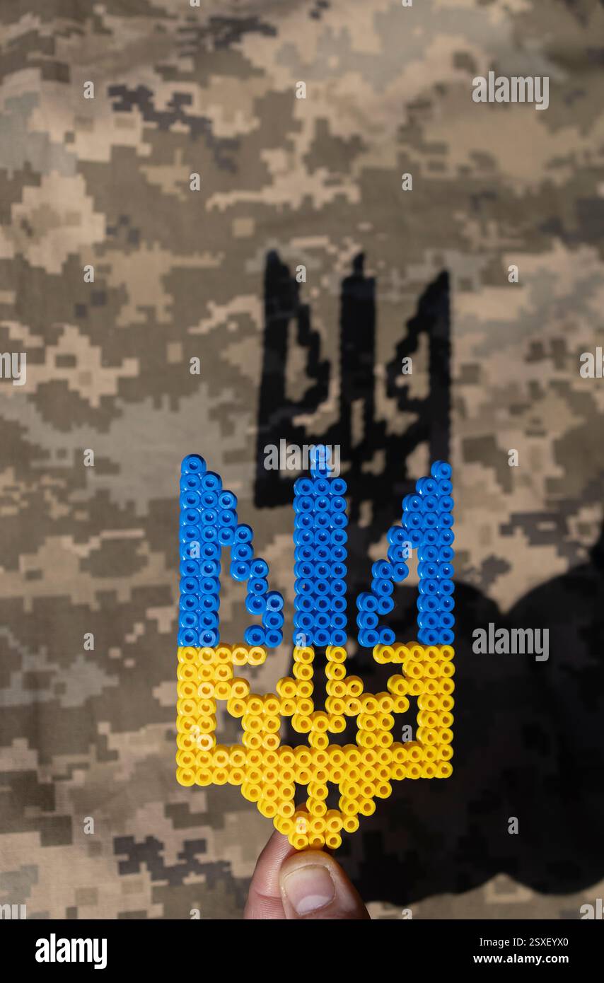 yellow-blue trident and its shadow on an army camouflage uniform Stock ...