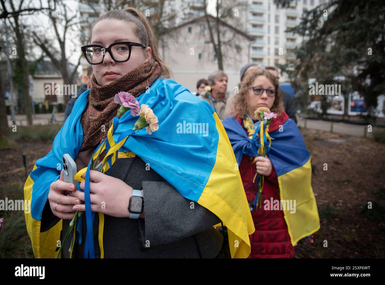 Women hold flowers and listen to speeches on the third anniversary of ...