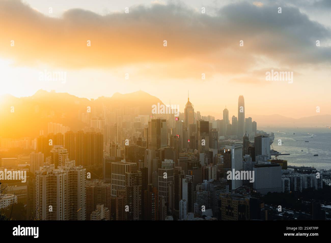 Breathtaking sunset over the Hong Kong skyline, casting a warm golden ...