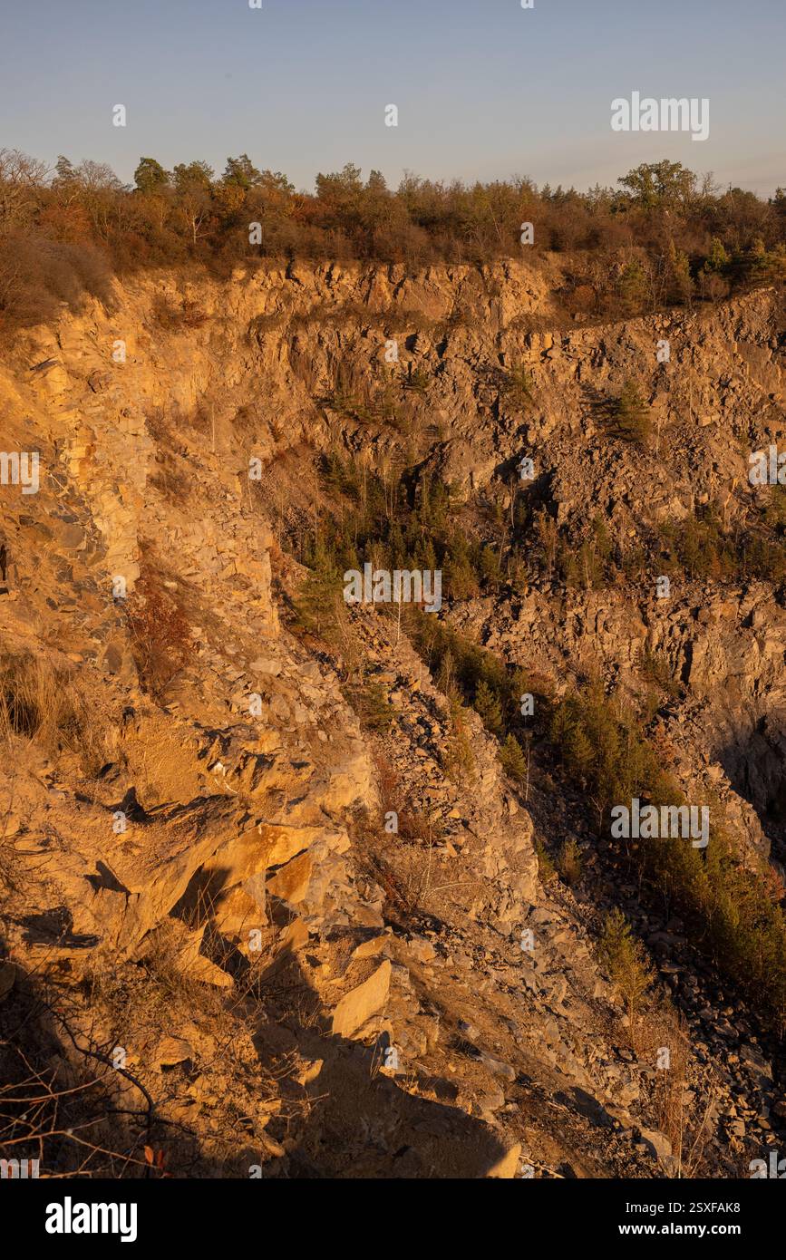 Rocky cliff with rough textures, golden sunlight, and sparse vegetation ...