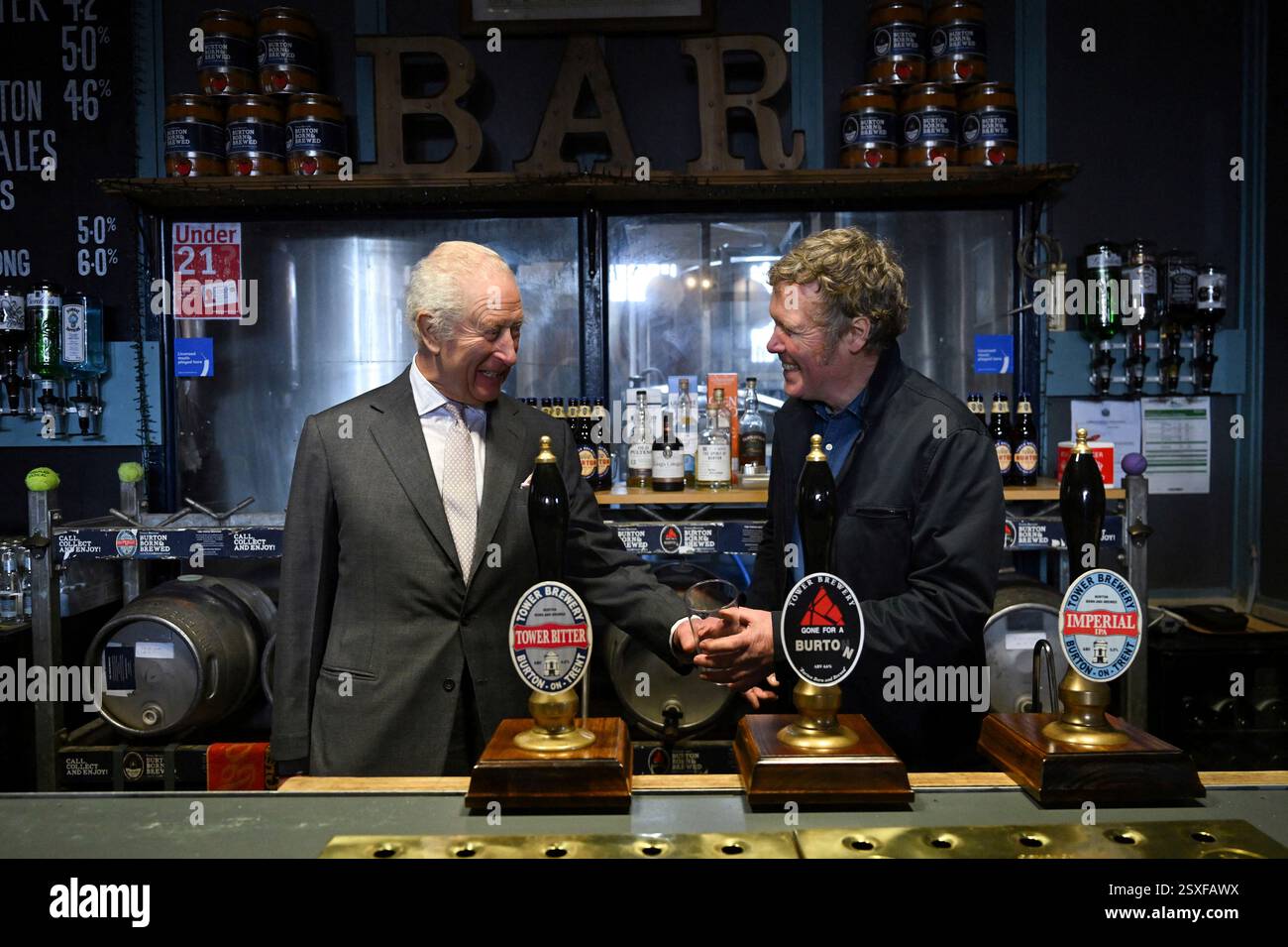 Britain's King Charles reacts with Tower Brewery owner John Mills, right, during a visit to the ...