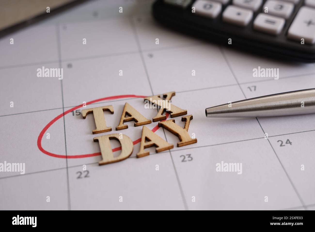 Tax day reminder marked on a calendar with wooden letters and office ...
