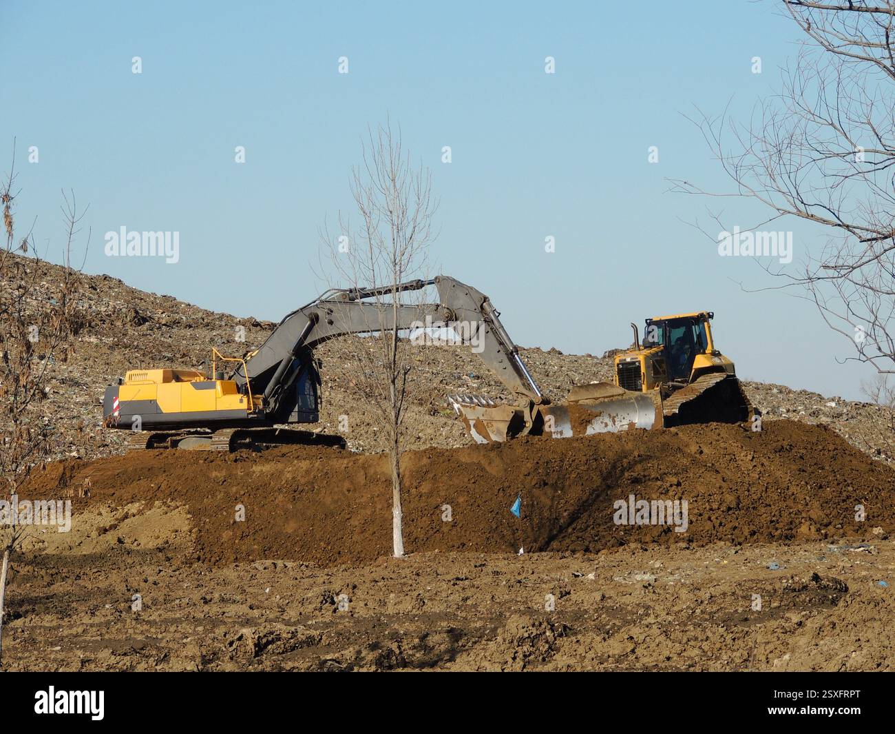land leveling with heavy machinery on earthen mound, excavator and ...