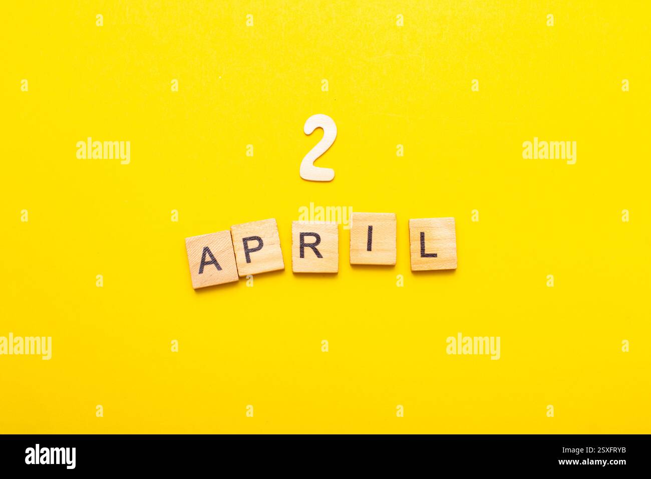 2 April calendar date made by wooden cubes on yellow color background ...