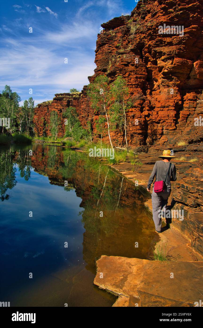 Woman walking on a narrow ridge along the river in the red rock canyon ...
