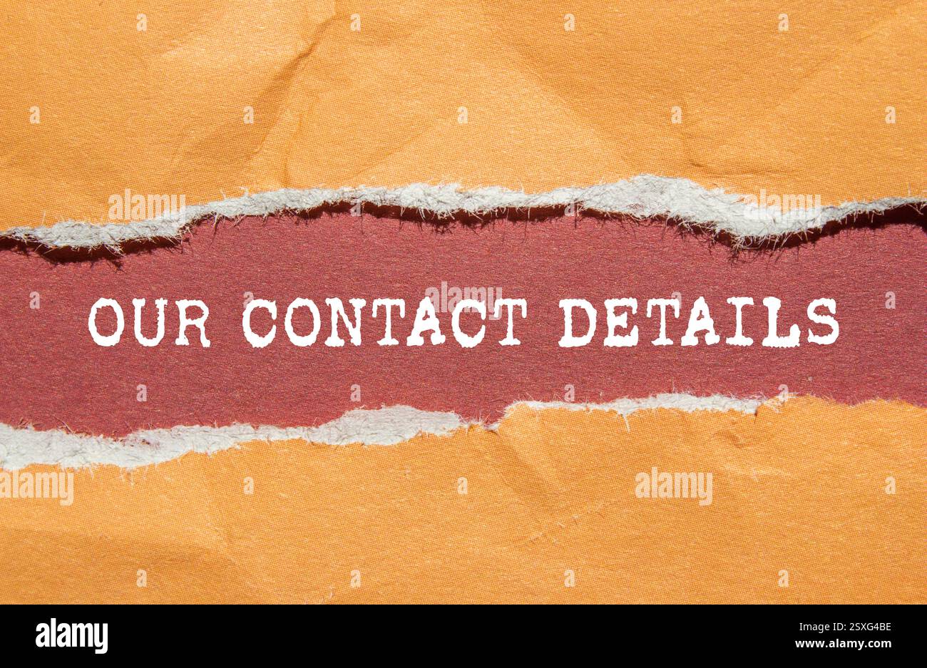 Our contact details message written on ripped torn orange paper on red background. Conceptual ...