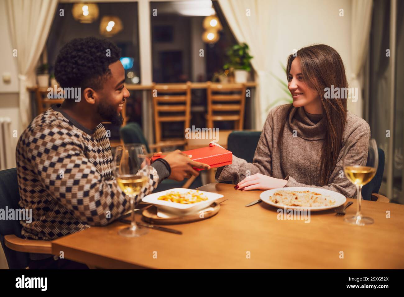 Two friends are having dinner at restaurant. They are exchanging gifts ...