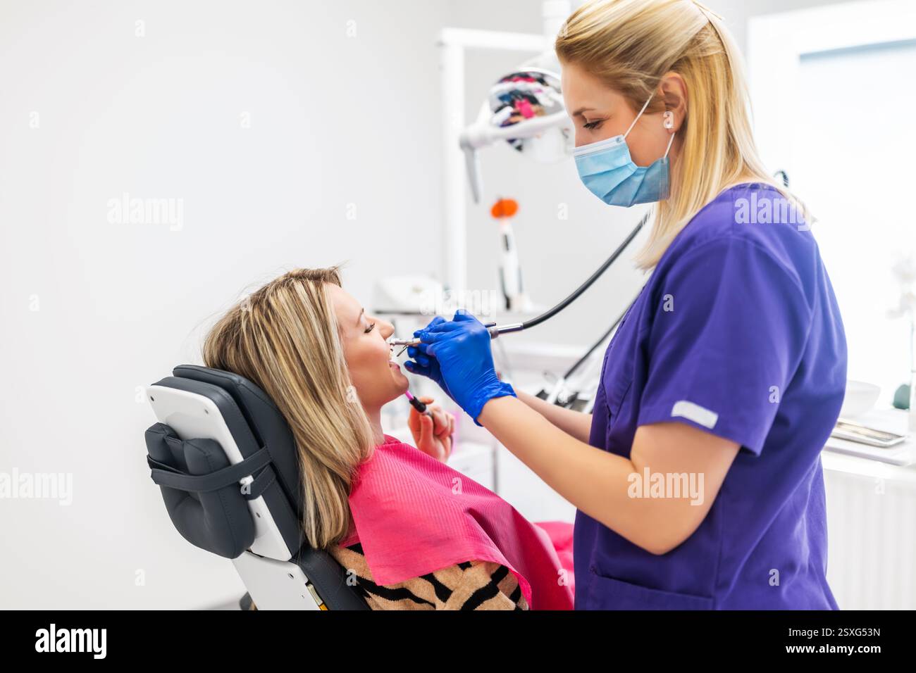 Dentist polishing the teeth of the patient. Young woman having her ...