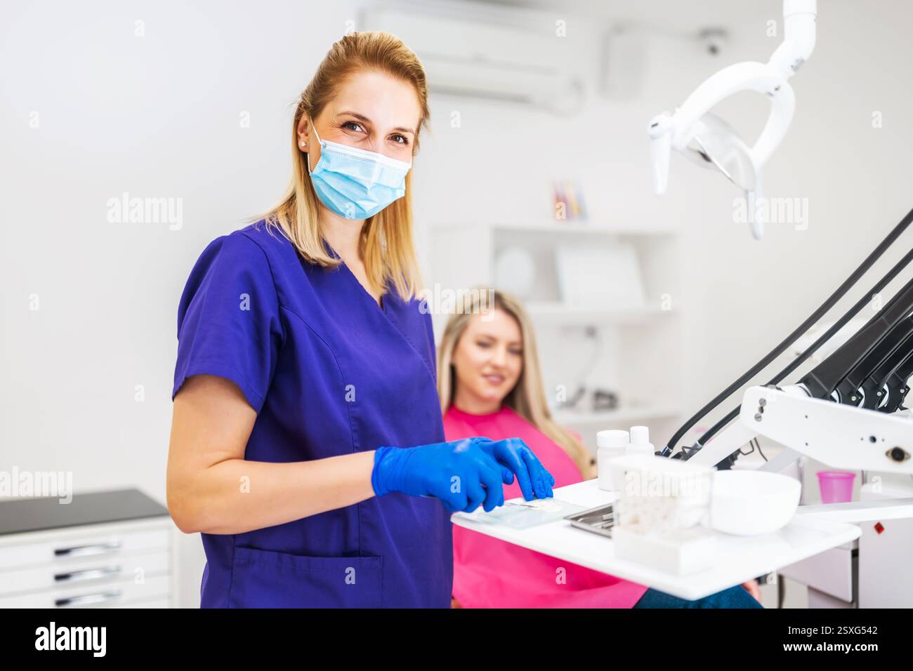 Dentist is repairing teeth of young woman. She is preparing dental ...