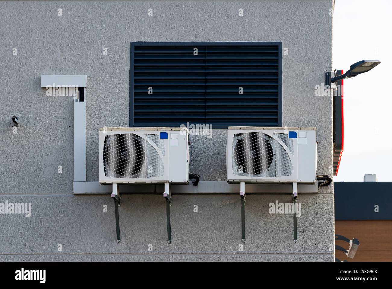 Two white air conditioning units are securely mounted on the exterior ...