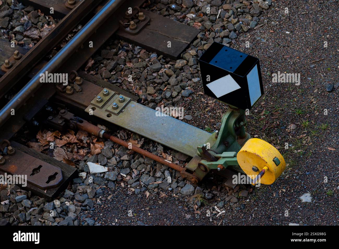 A yellow wheel railway switch mechanism is positioned beside tracks ...