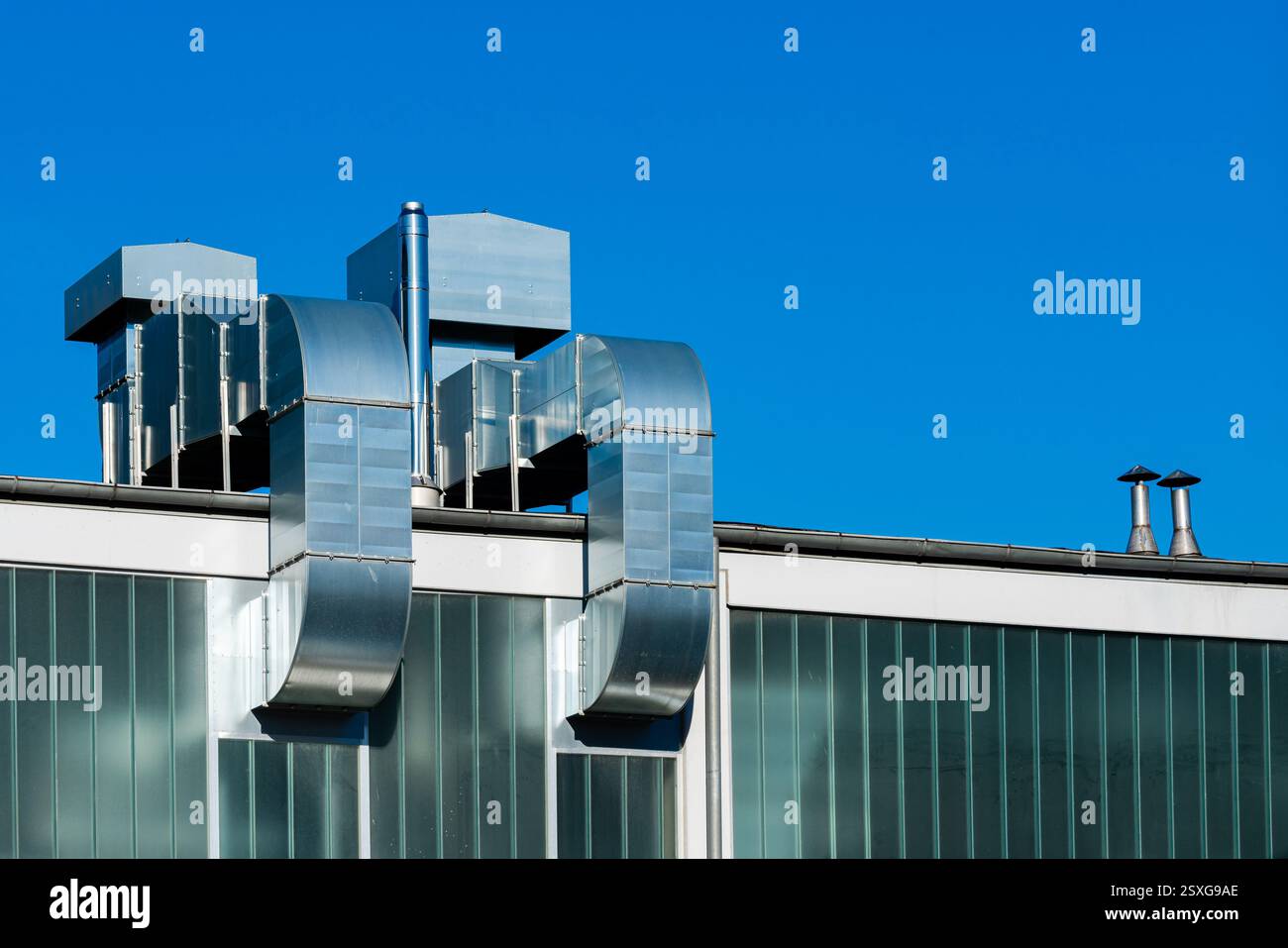 Metal ventilation pipes and ducts are seen on a modern building against ...