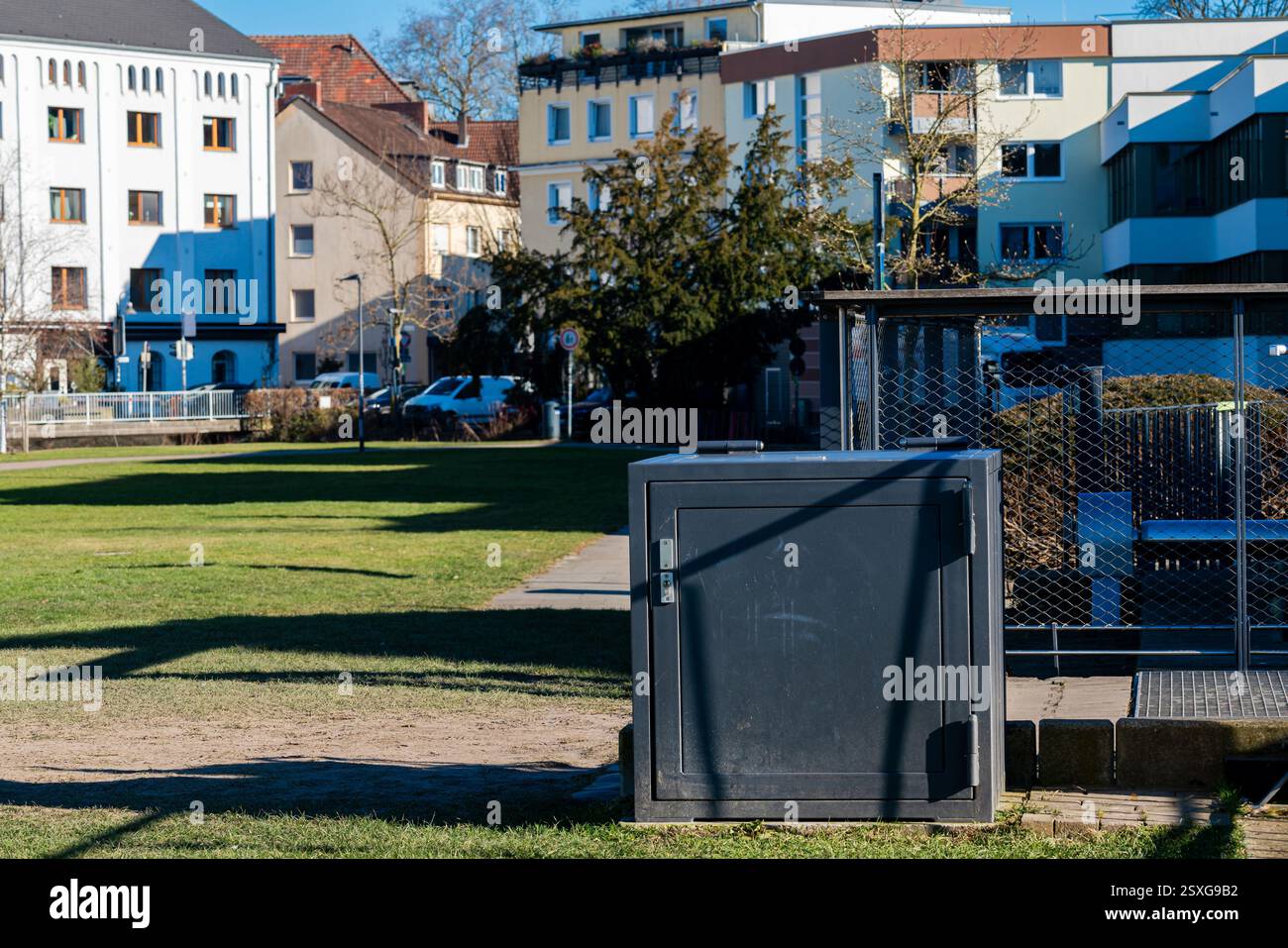 A utility box stands prominently in the foreground of a sunny urban ...