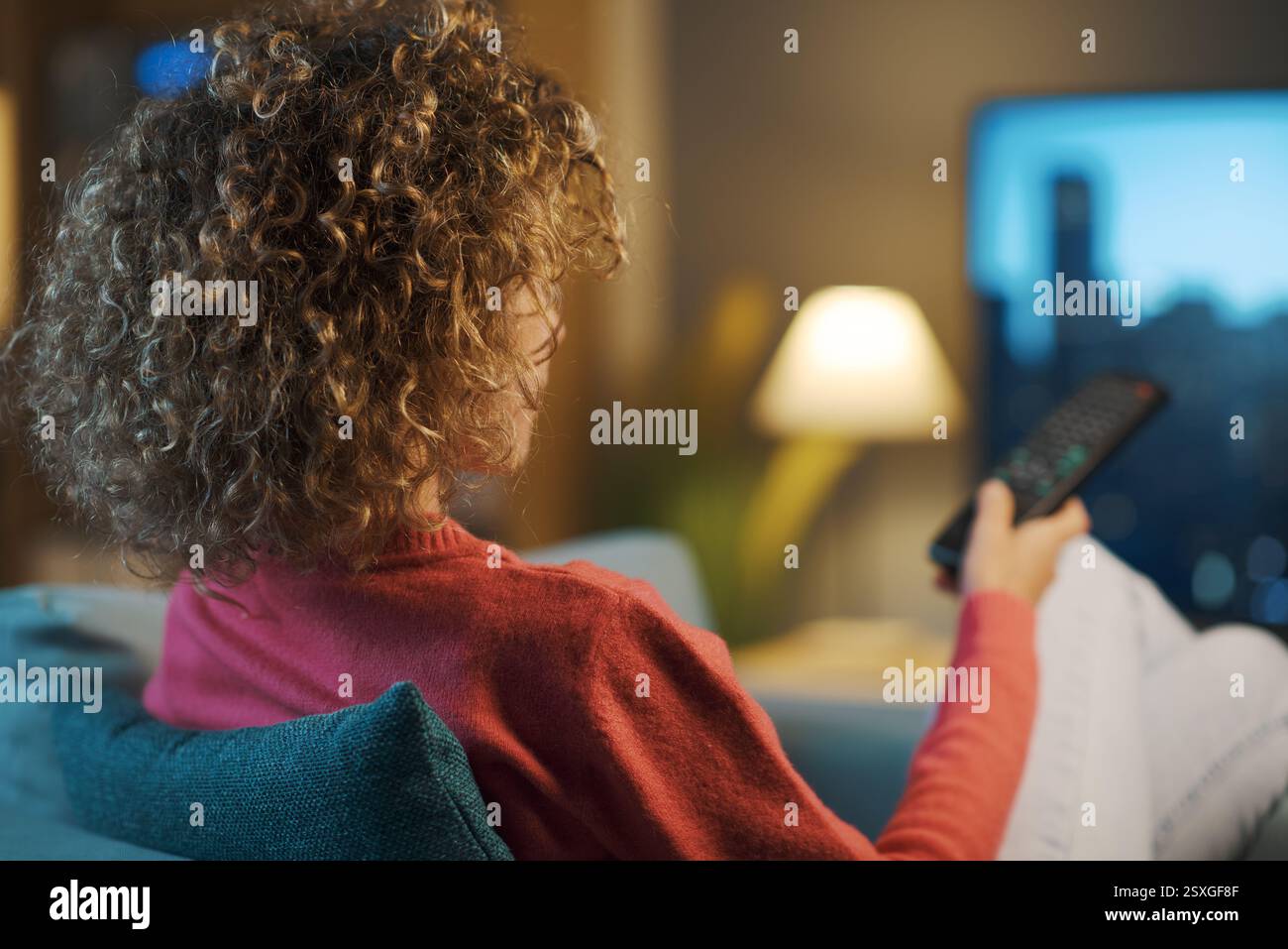 Woman relaxing at home alone at night, she is holding the remote ...