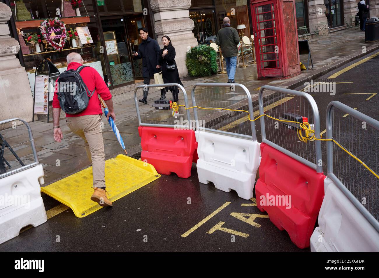 Members of the public walk through barriers and a ramp that takes them ...