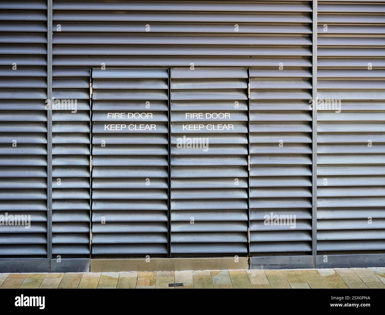 Metal fire door with warning sign against a ribbed steel wall Stock ...