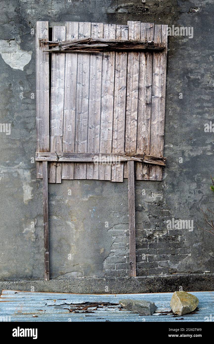 Weathered wooden boards lean against a crumbling wall, revealing signs ...