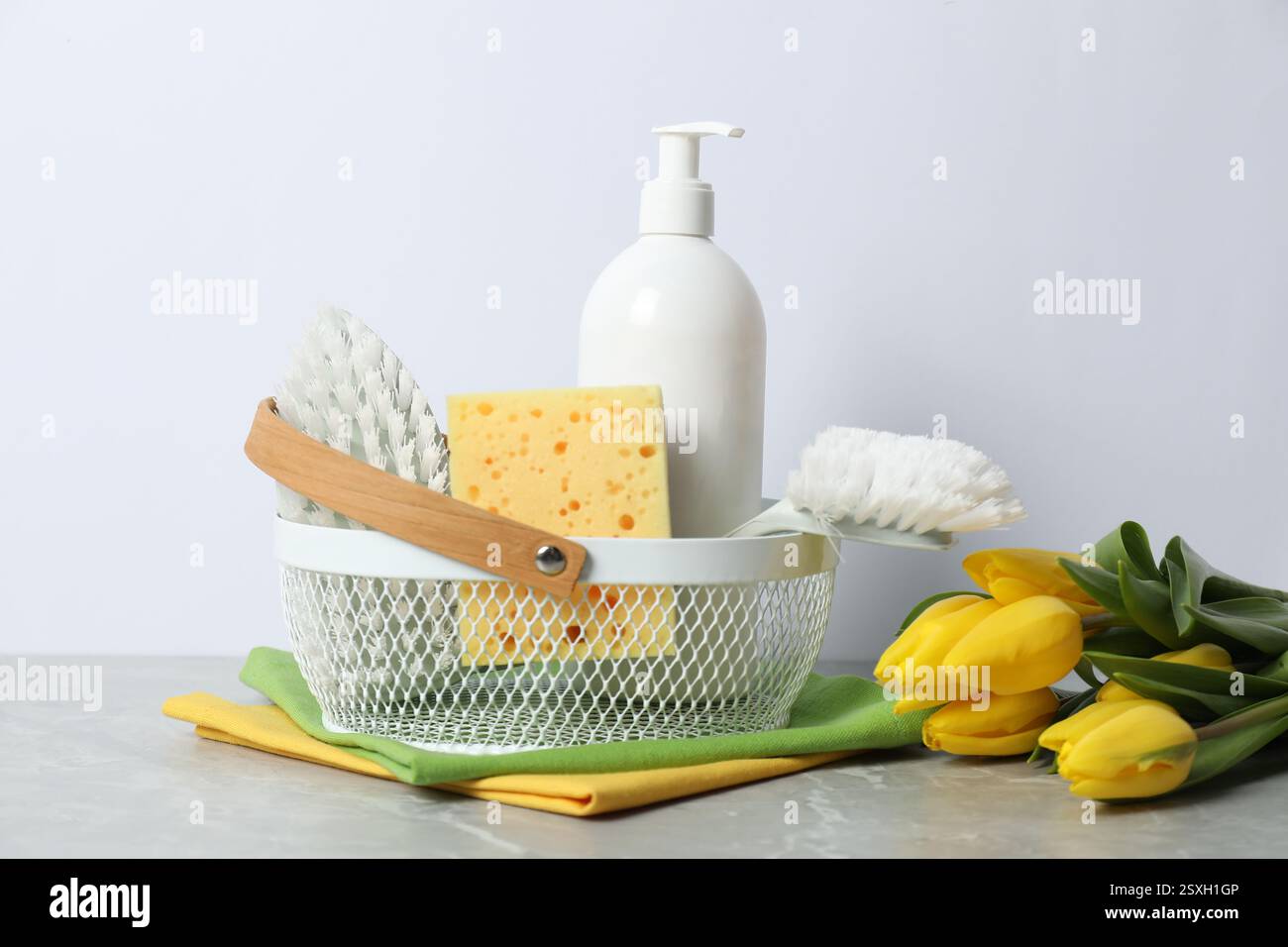 Spring cleaning. Detergent, supplies and tulips on light grey table ...