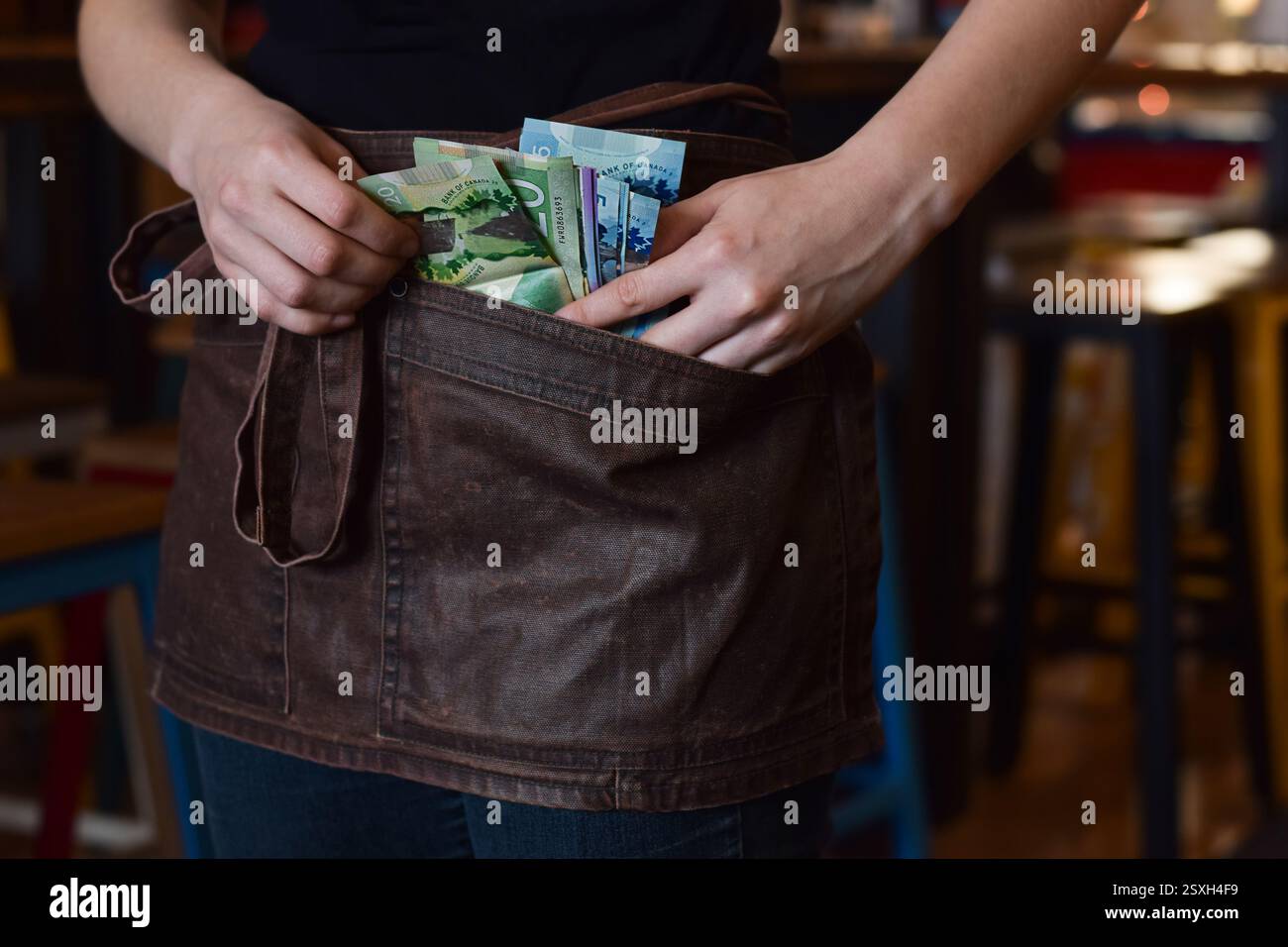Server using pockets of her apron to keep cash money tips Stock Photo ...