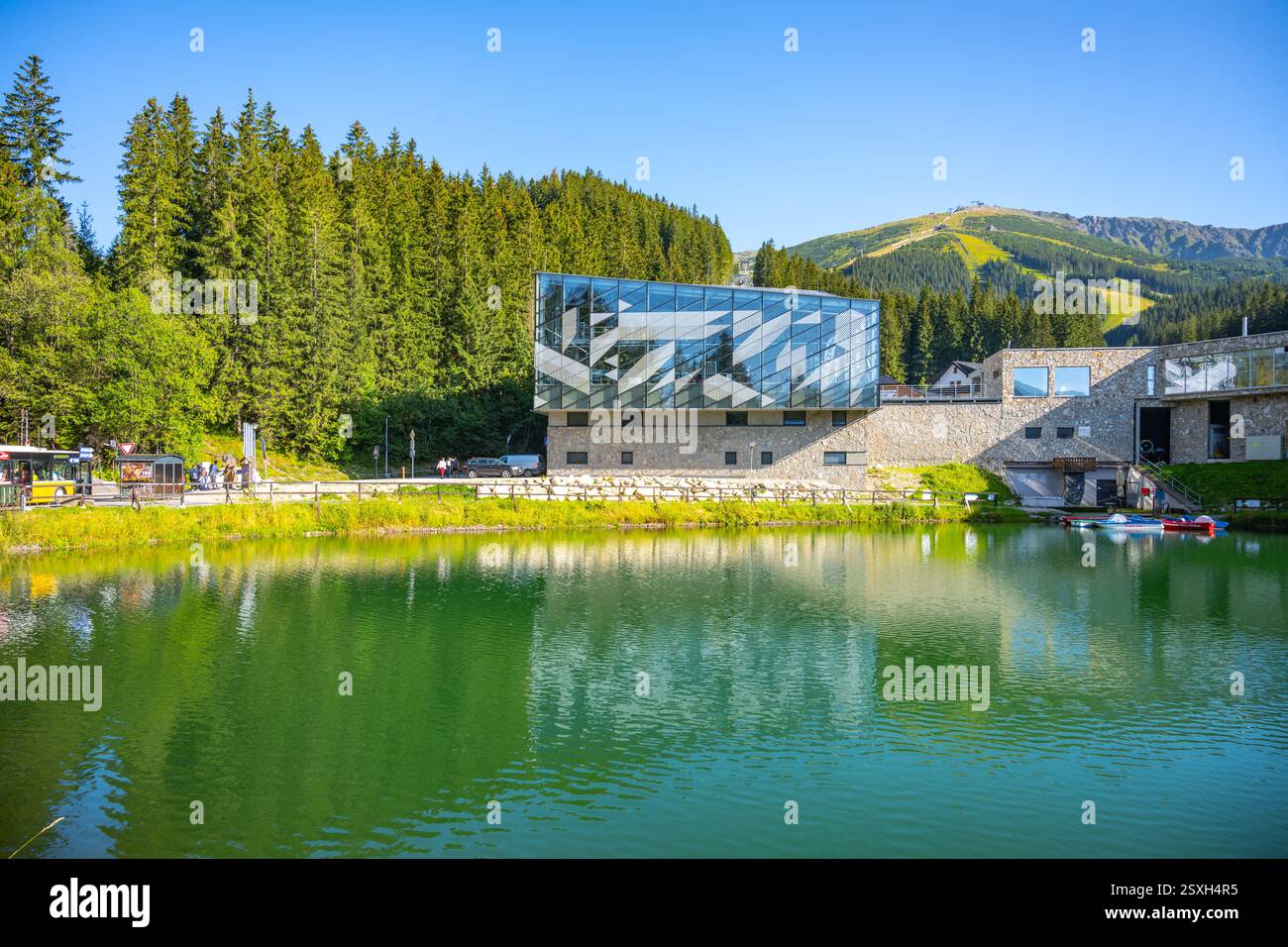The tranquil waters reflect the modern architecture of Jasna Ski Resort ...
