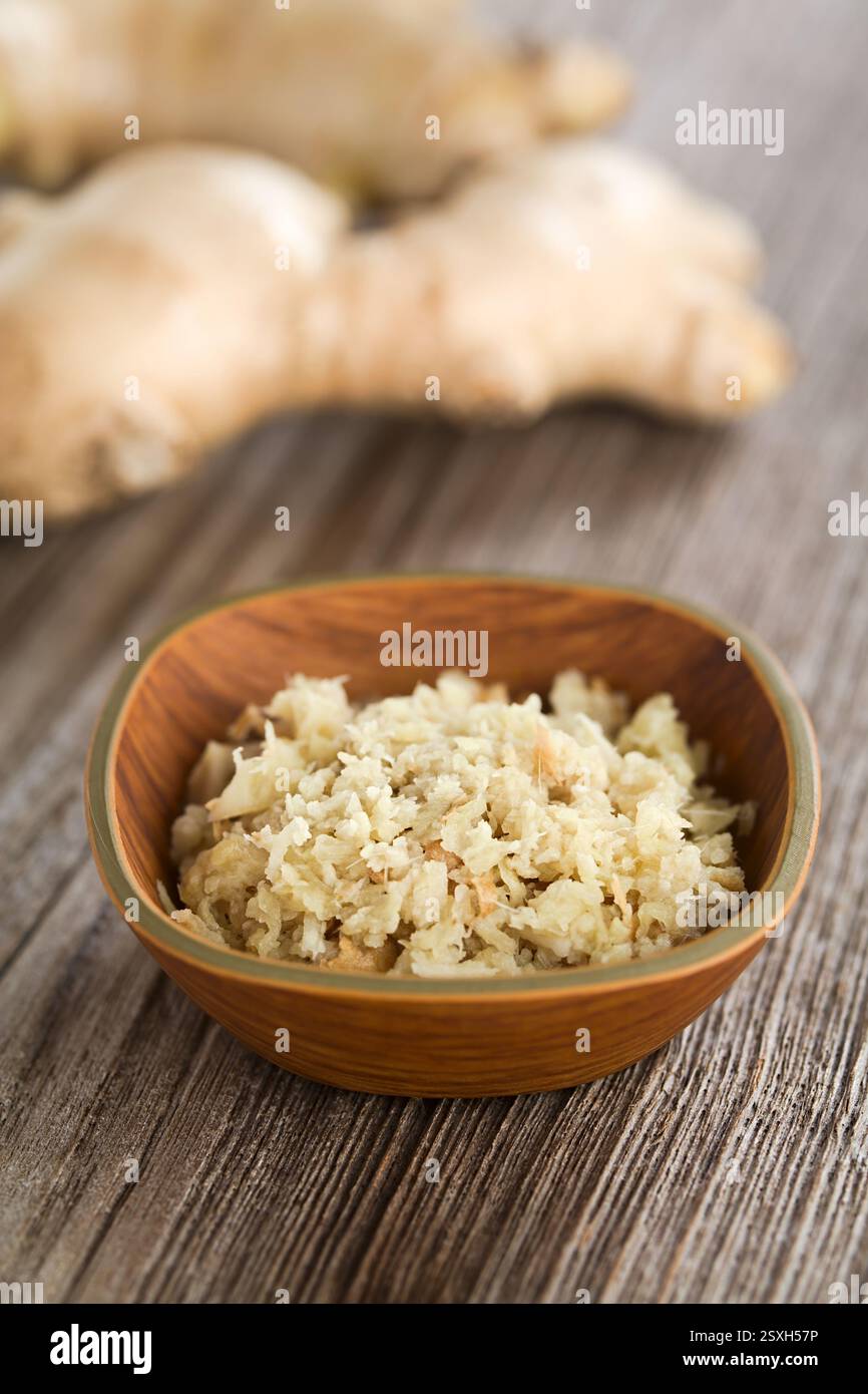 Freshly grated ginger in small bowl with ginger roots in the back (Selective Focus, Focus one ...