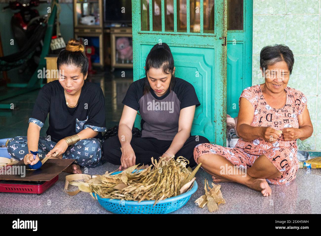 Three women engaged in traditional craft work inside a home on Cu Lao ...
