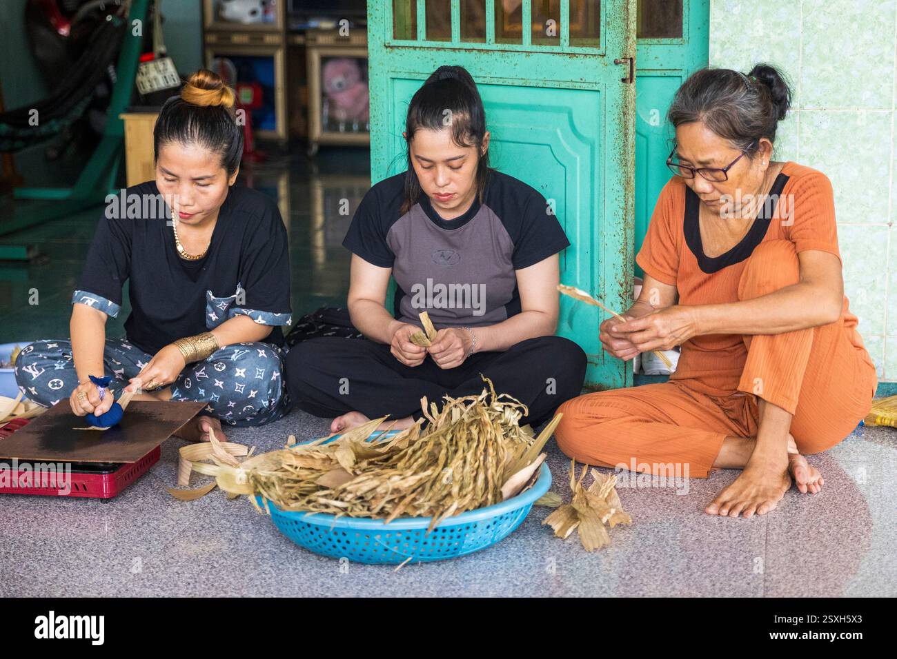 Three women engaged in traditional craft work inside a home on Cu Lao ...