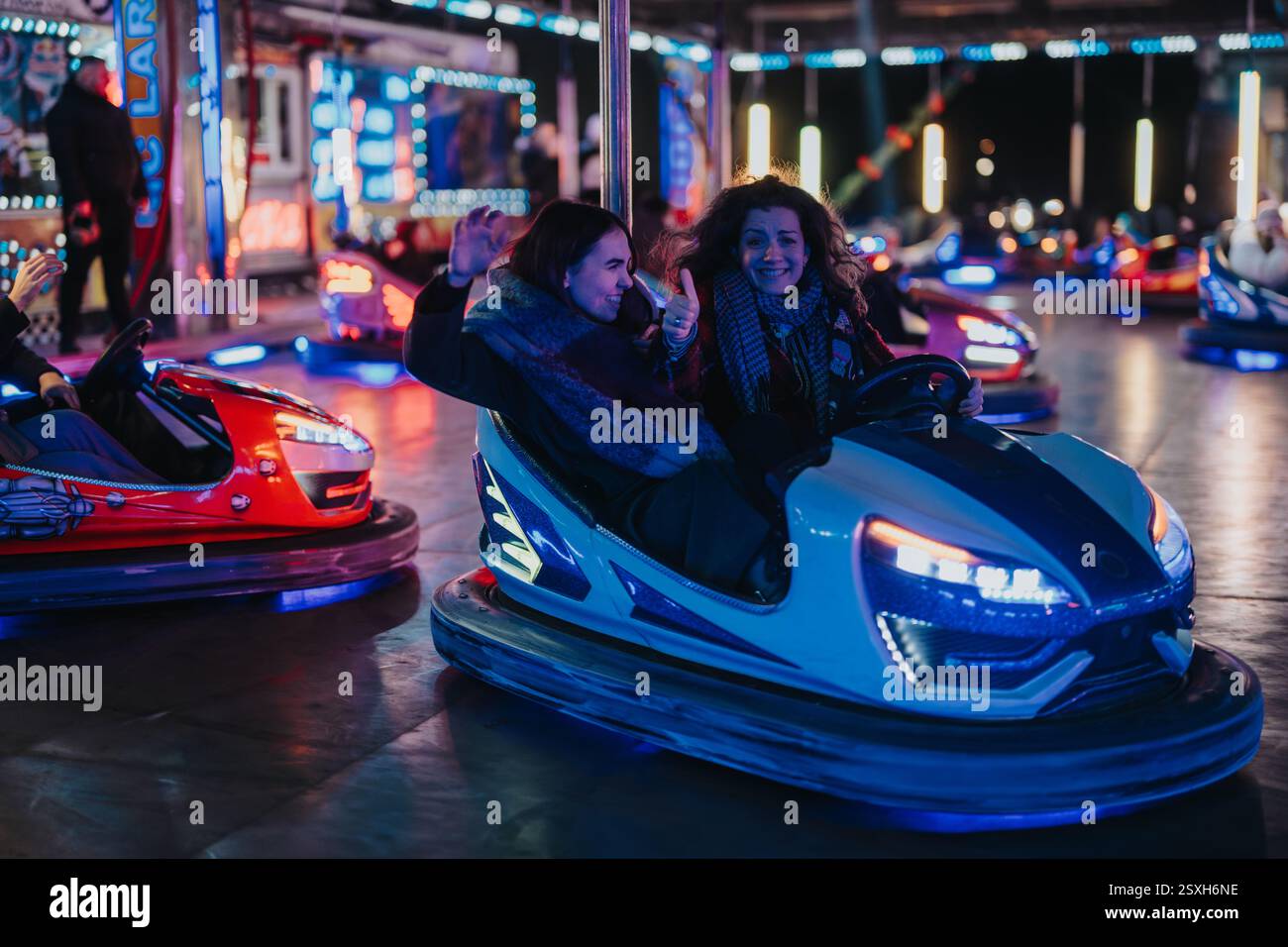 Women enjoying bumper cars at a fairground with vibrant lights and ...