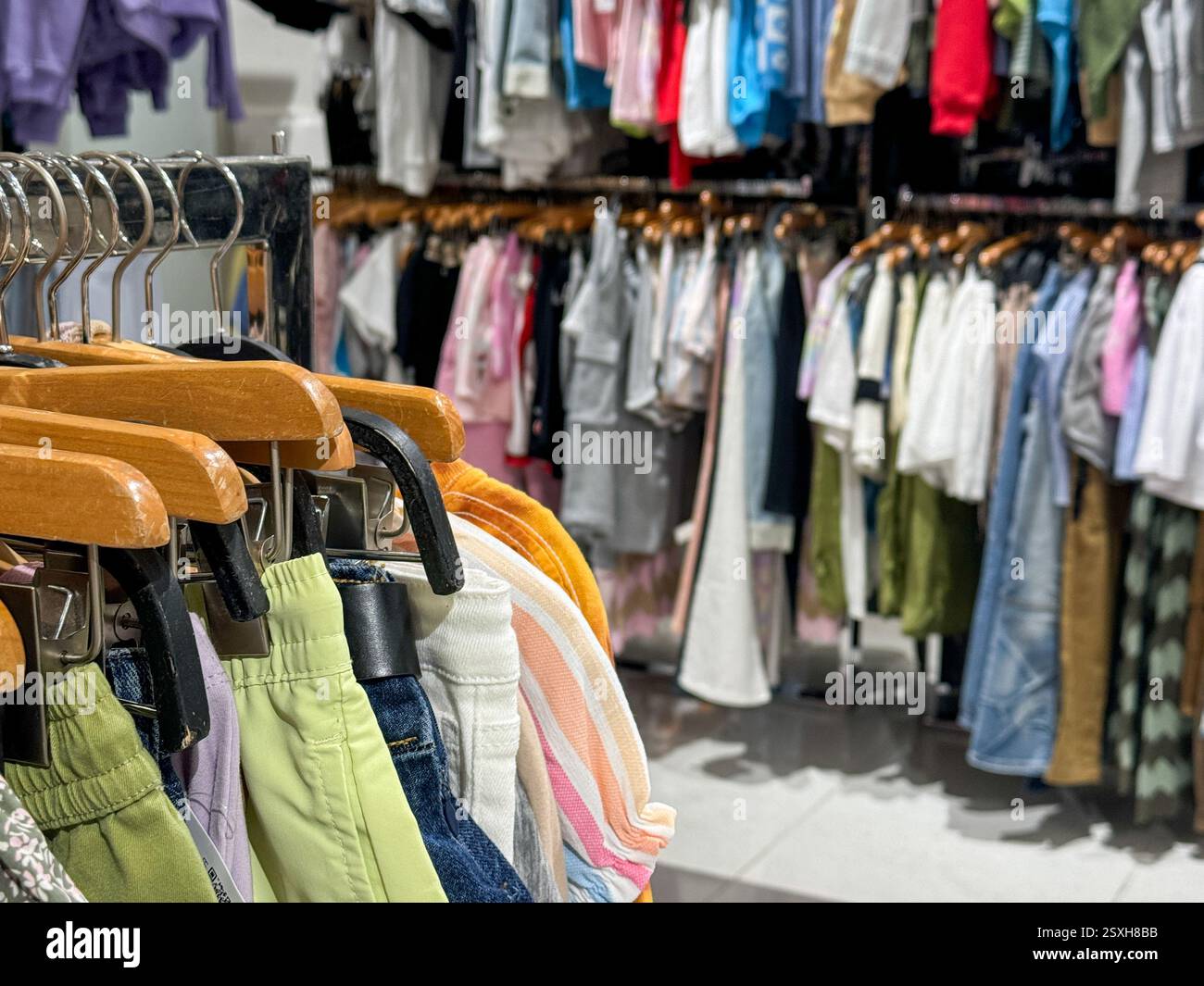 A clothing store with racks full of colorful garments, including pants ...