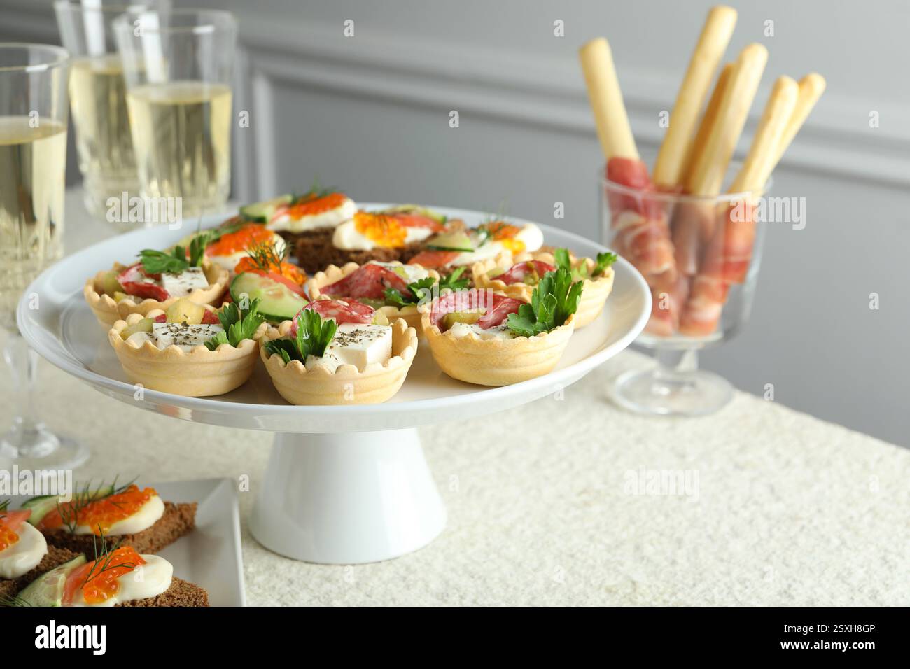 Many different tasty canapes and wine on white table Stock Photo - Alamy