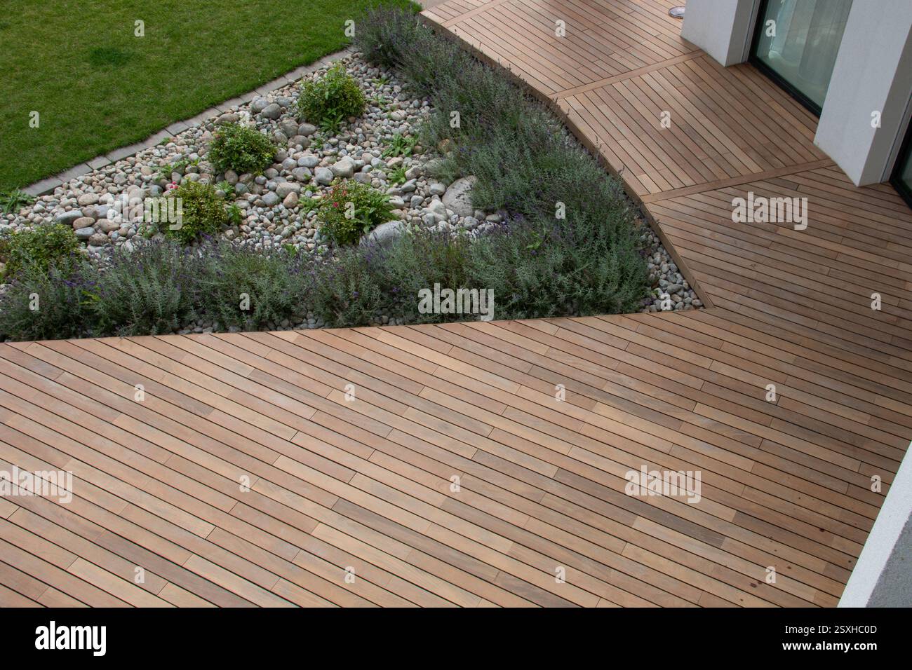 Outdoor patio designed with wooden decking and landscaped garden ...