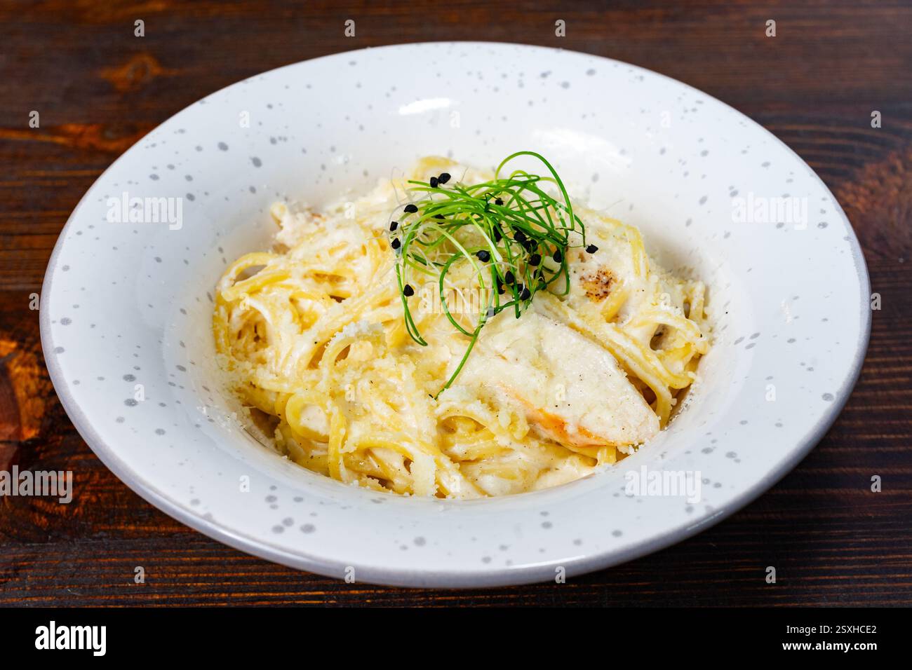 A plate of creamy pasta served with delicate herbs and a sprinkle of ...