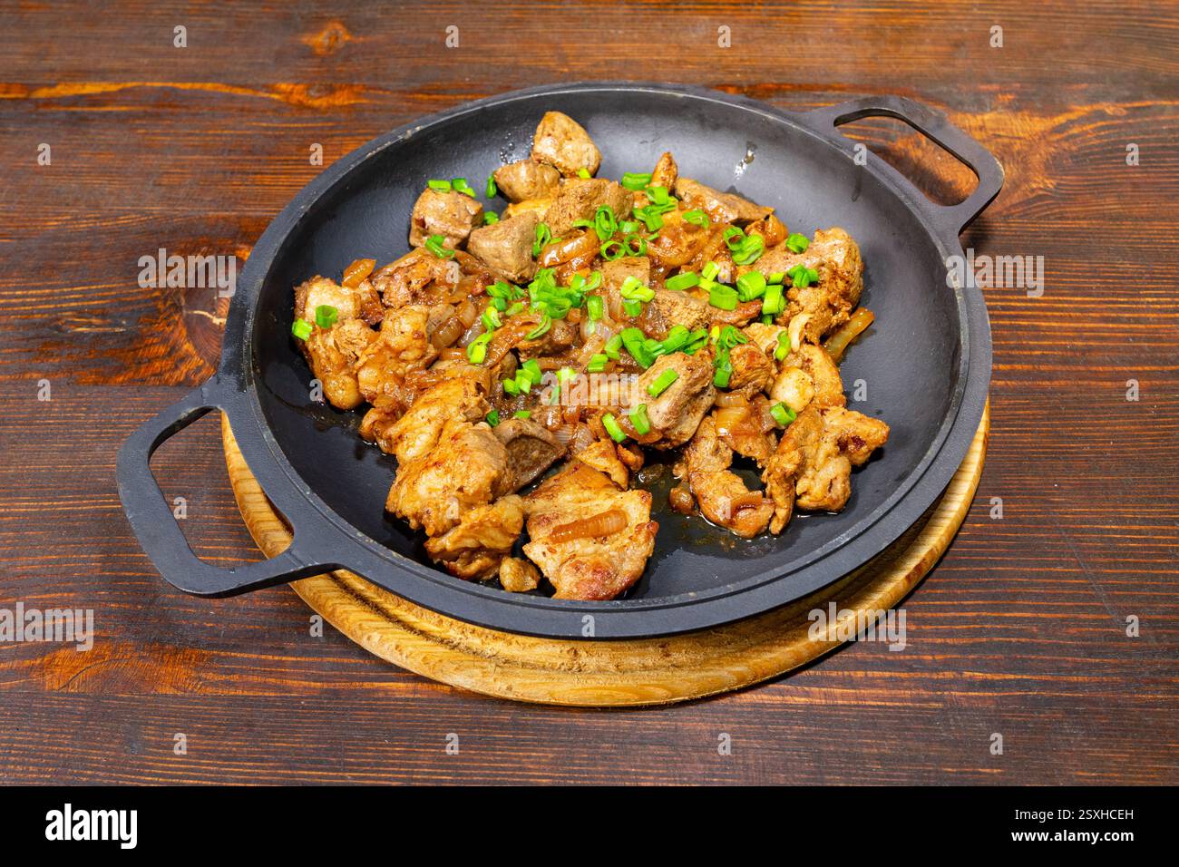Sizzling pieces of marinated meat cooked with aromatic spices lay on a ...