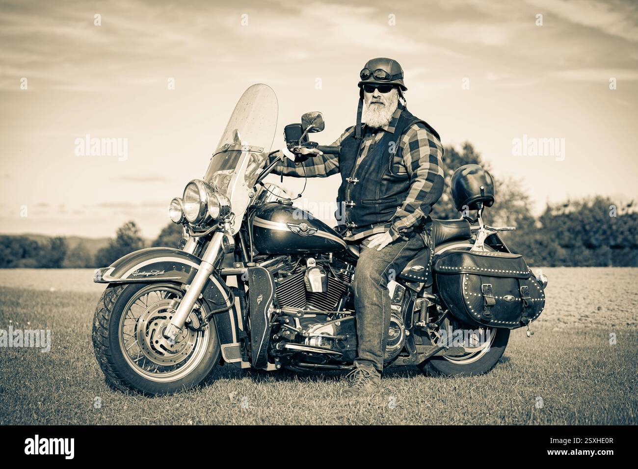 Rocker mit schöner Harley-Davidson possiert auf einer Landstraße, Sepia ...