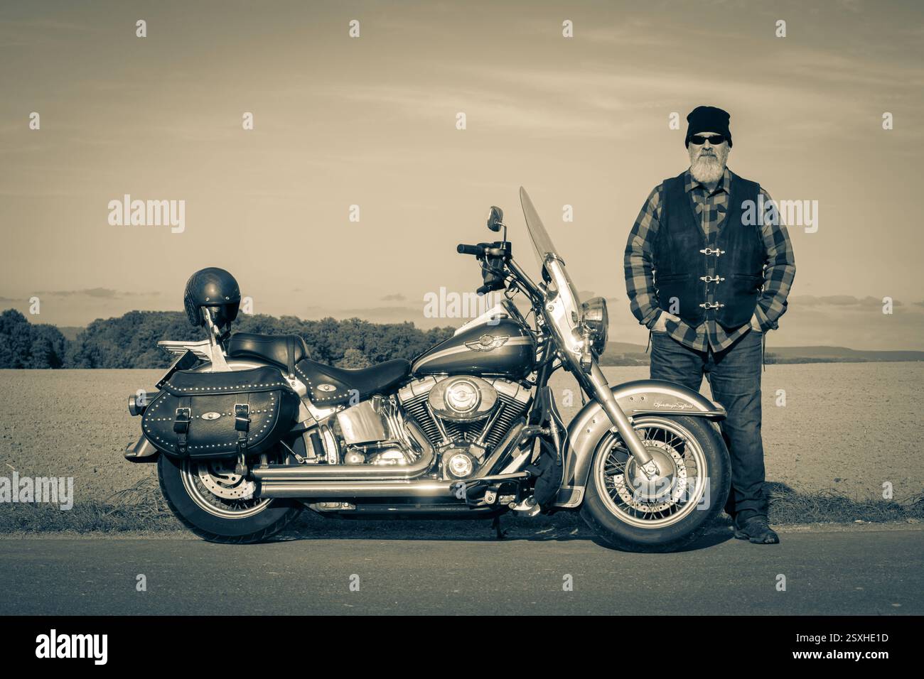 Kultiger Motorradfahrer posiert mit seiner alten Harley Davidson, sepia ...