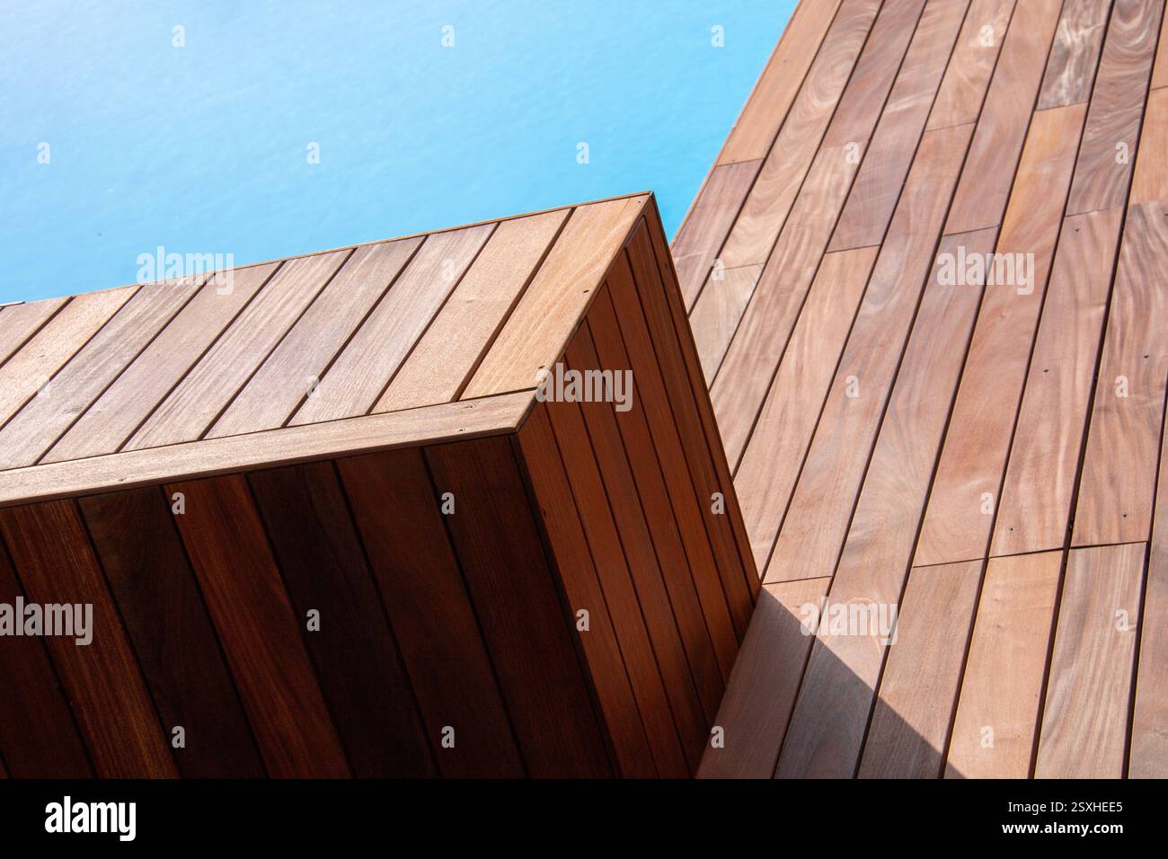 A wooden deck surrounds a refreshing blue swimming pool, showcasing ...
