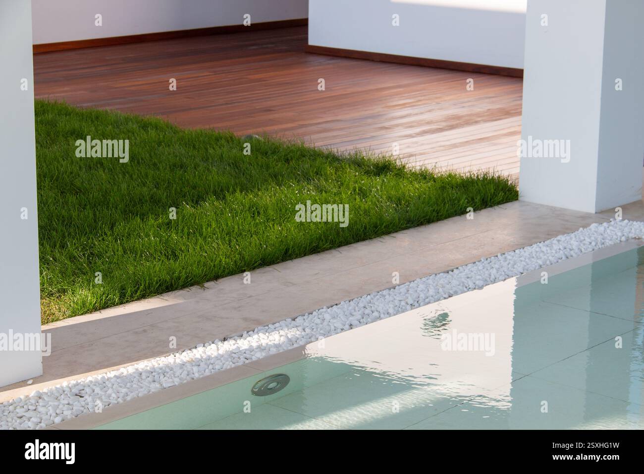 Modern architectural design with wood flooring, grass area and water ...