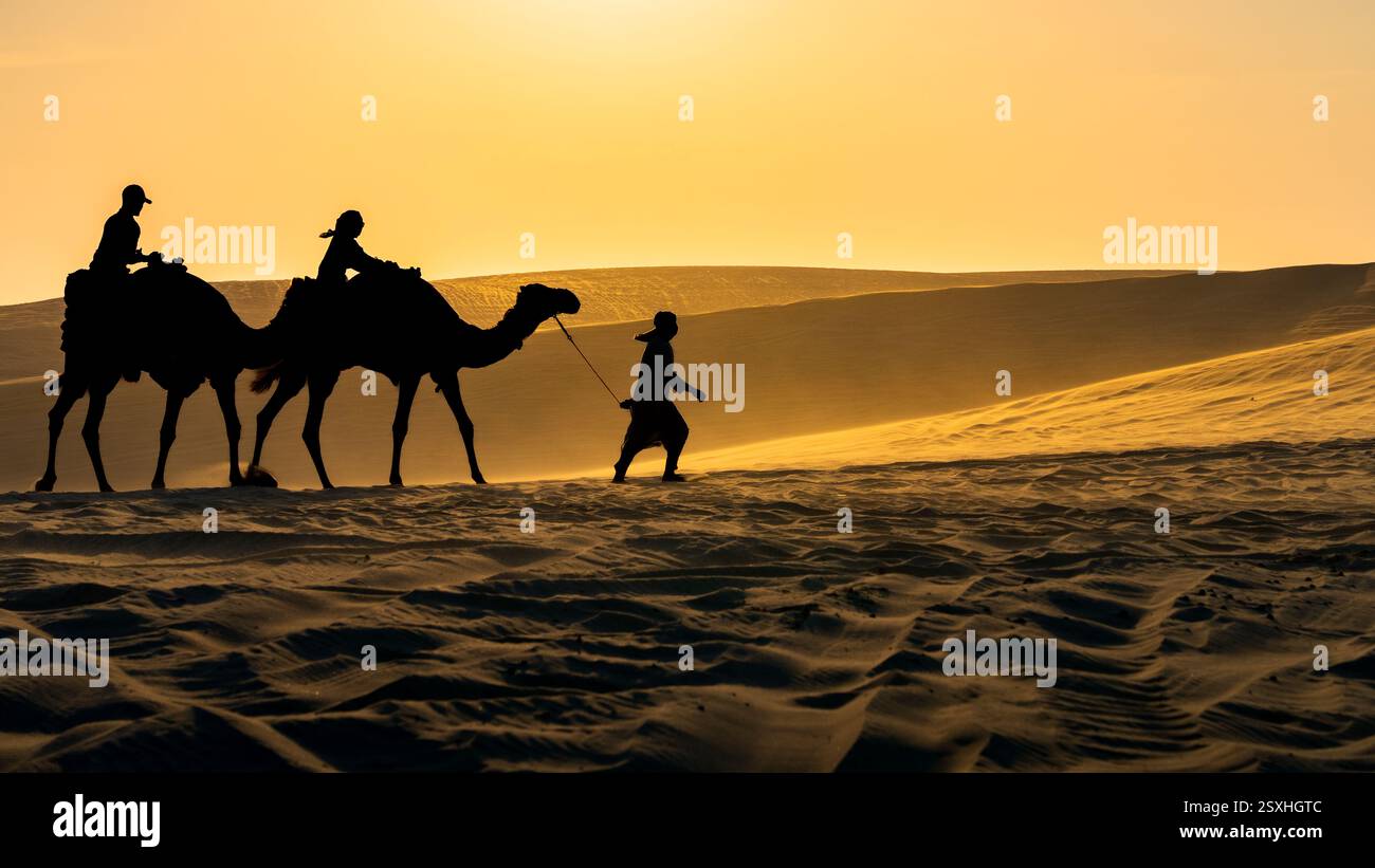 Doha, Qatar, February 24, 2025: A group of people riding camels through ...