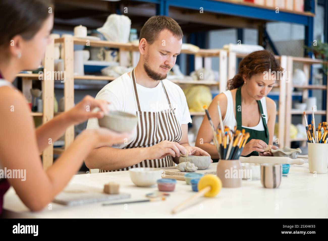 Three students in pottery workshop learn to create homemade plates and ...