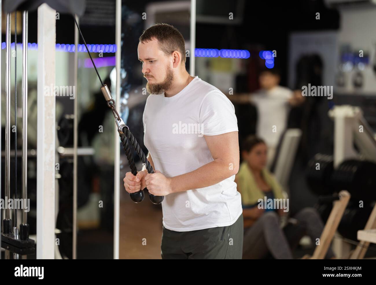 Man in gym performs exercises for arm muscles using cable crossover ...
