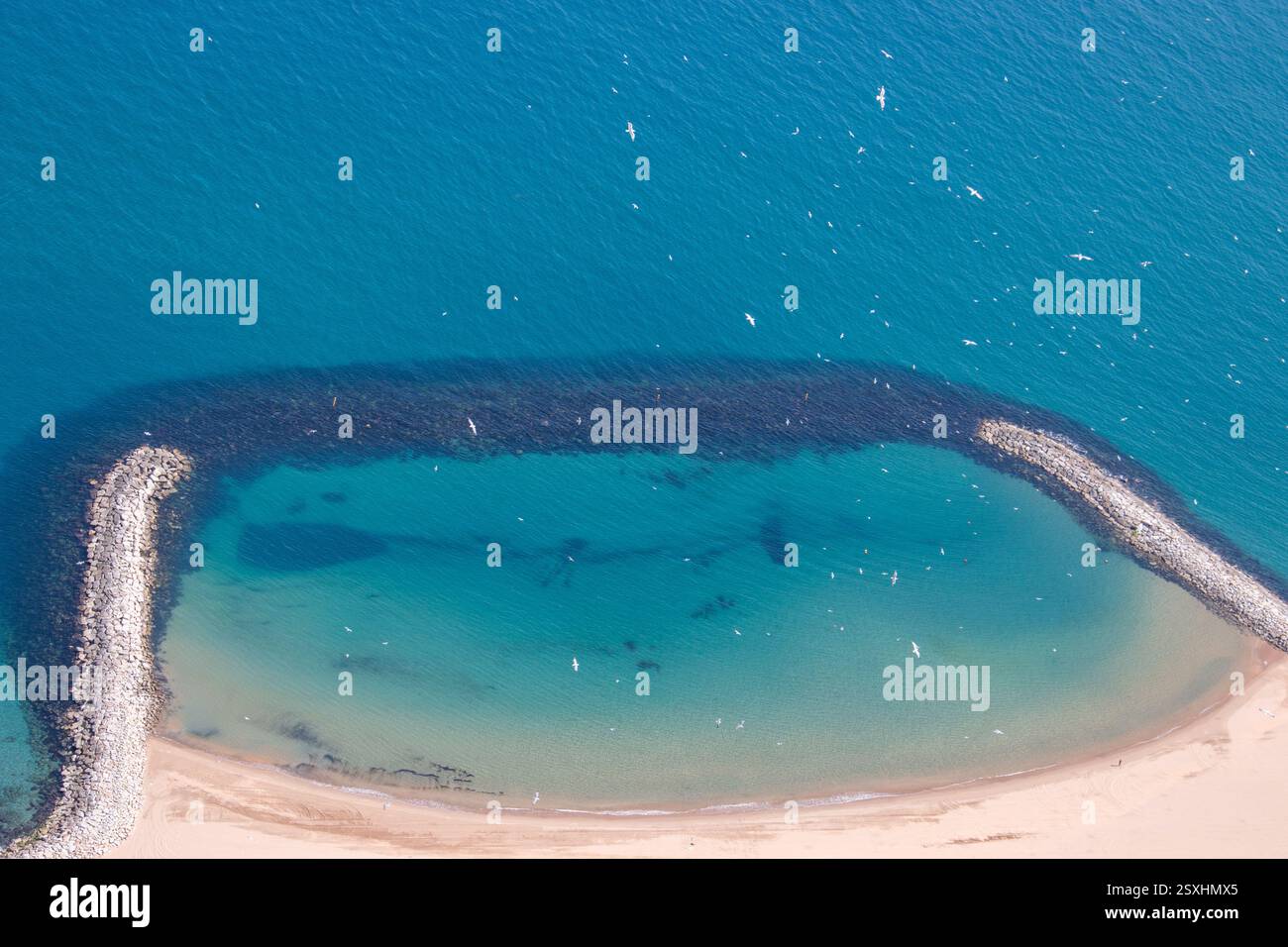 Sandy beach between two shore protection rocky barriers aerial view ...