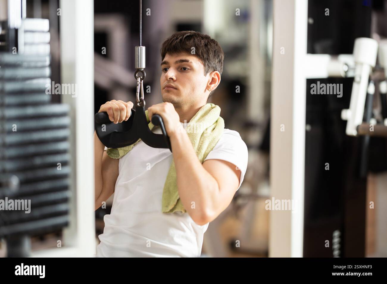 Guy in gym performs exercises for arm muscles using cable crossover ...