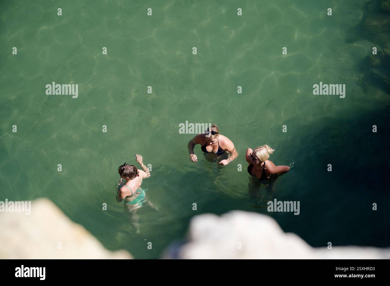 Three women enjoy a refreshing swim in the clear green waters of Santa ...