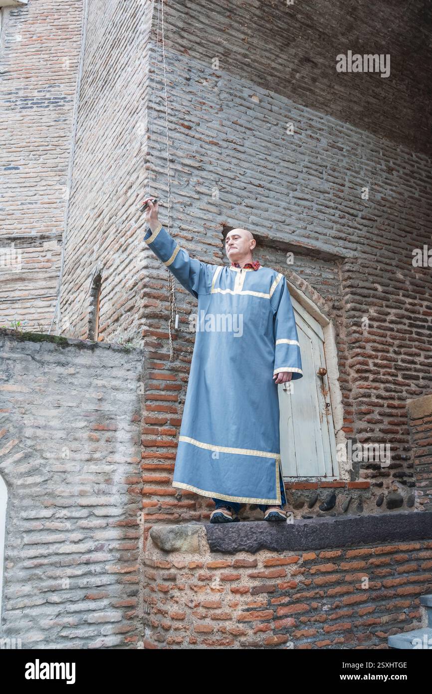 A bell ringer rings large church bells under the open sky. A ...